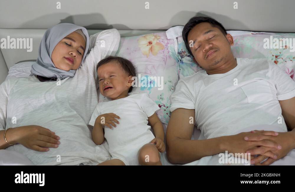 Little girl crying while their parents sleeping Stock Video Footage - Alamy