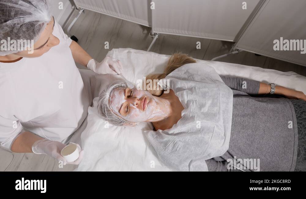 doctor applies an anesthetic cream on the face of his patient lying ...