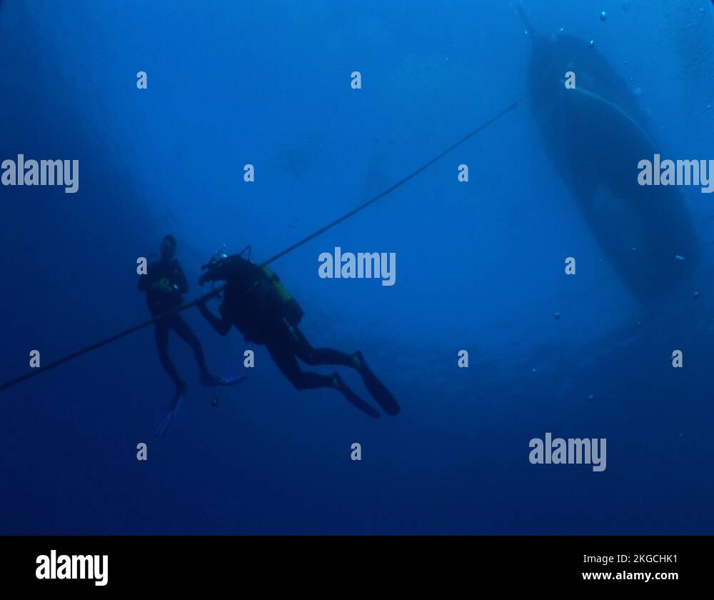 scuba divers silhouette descending ascending underwater sun and boat ...