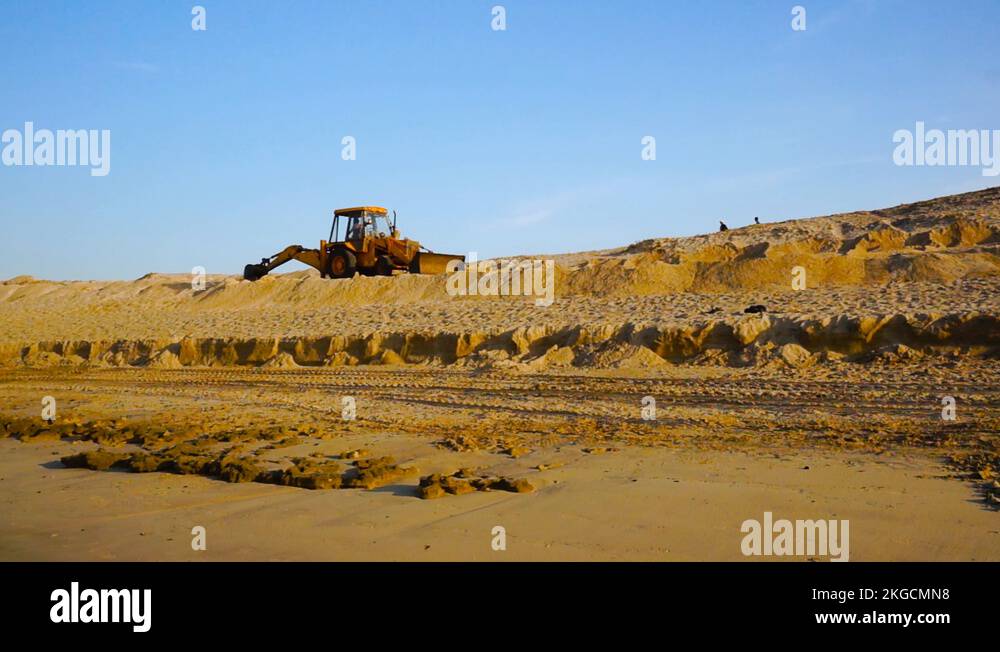 construction equipment back hoe loader digging sand on a beach in ...
