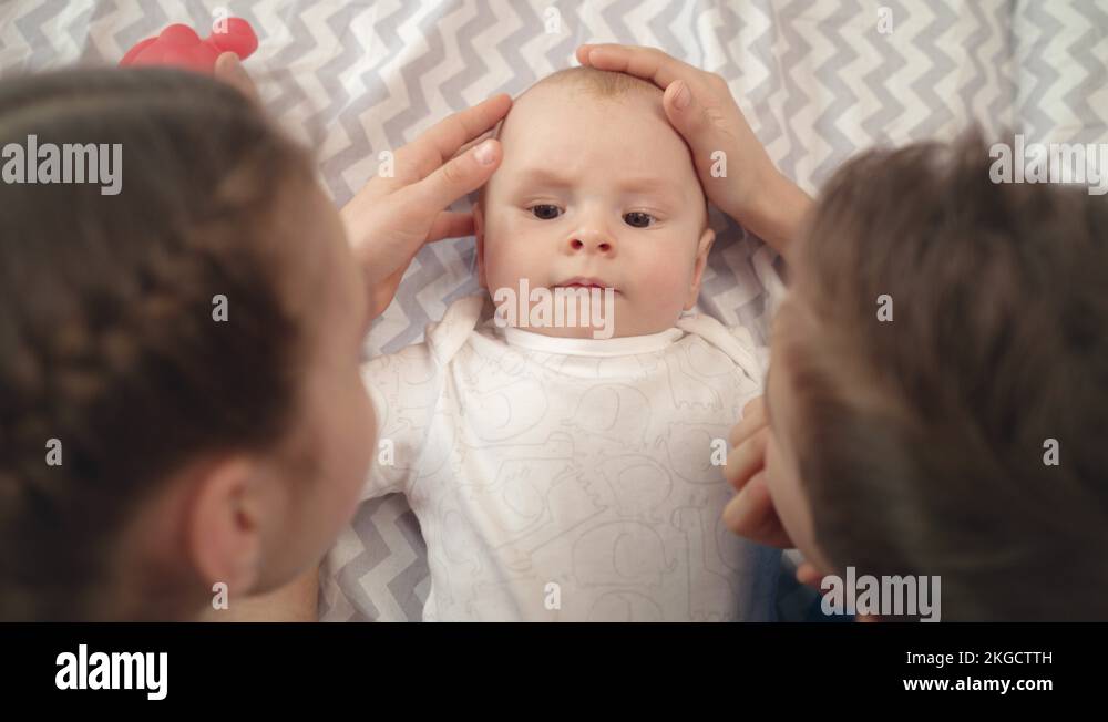 Beautiful baby face. Close up of siblings touching baby boy lying on ...