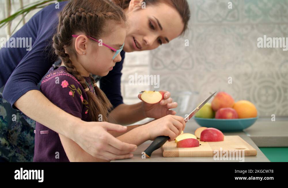 Mother learnig dauther using knife. Little girl cutting apple slice ...