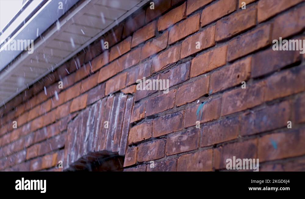 Heavy snow falling from the roof top of a house. Close up of snow ...