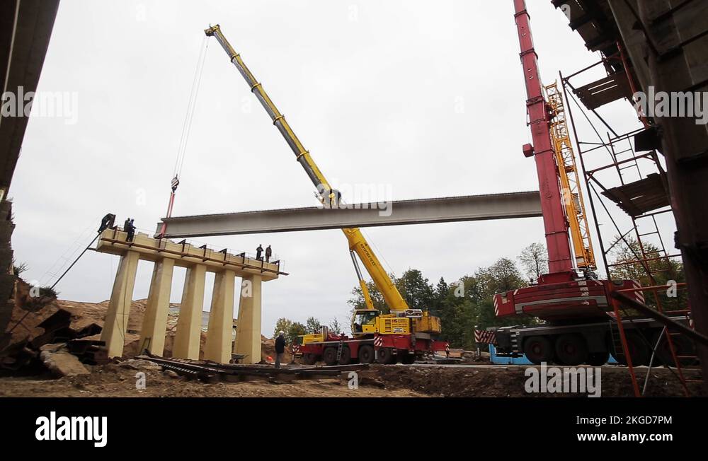 Bridge construction, workers in helmet work, concrete beam is moved by ...