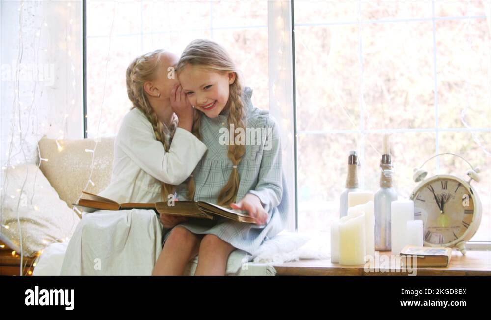 Portrait of two girls with long braids share secrets and giggle on ...
