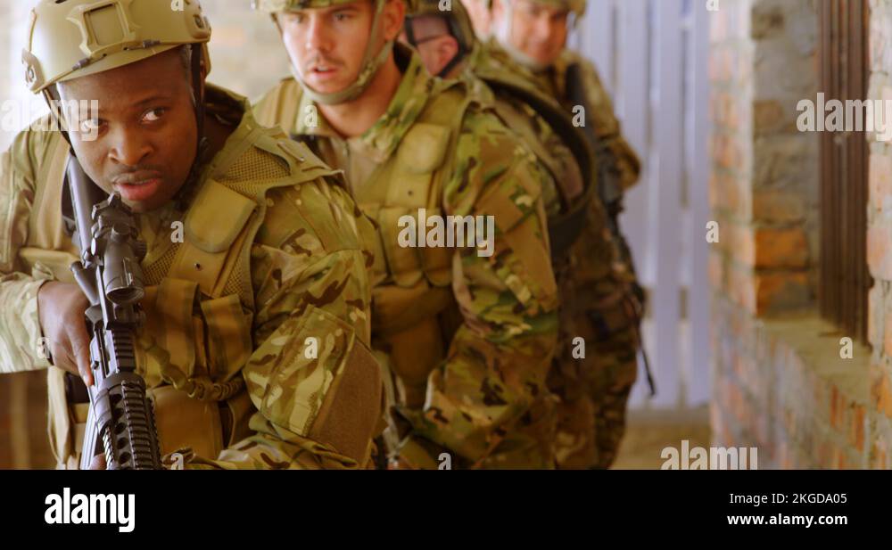 Front view of mixed-race military soldiers walking with rifles during ...