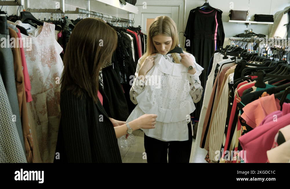 Two happy young girls are choosing clothes in a department store. 4K ...