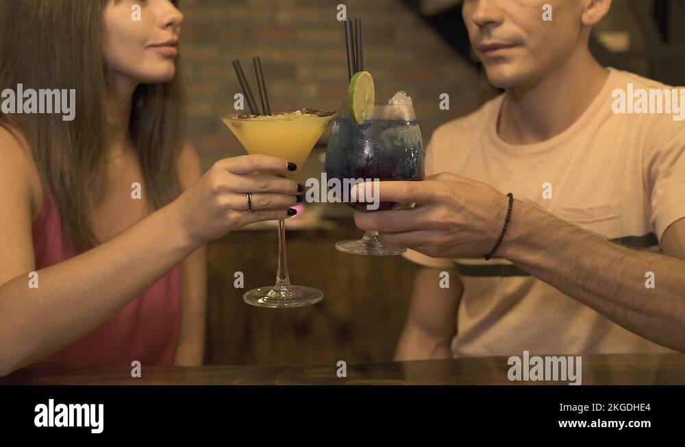 Man and woman holding in hands long drink cocktail and clink glasses in ...