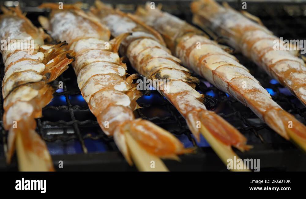 Cooking seafood on barbecue grill. Grilled tiger prawns, filmed in 4K ...