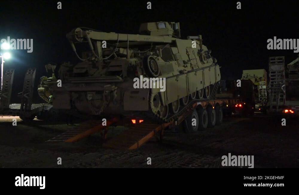 Military vehicle tracking up ramp of low loader trailer ramp for ...