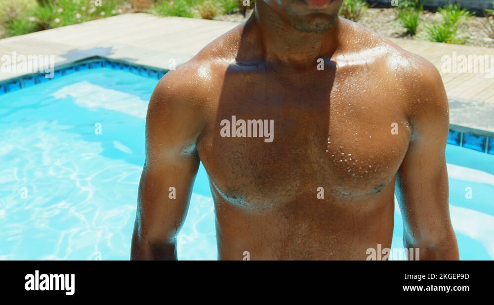 Front view of young black man standing in the swimming pool at resort ...