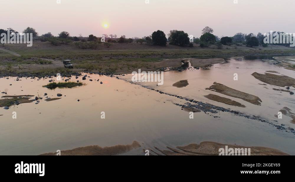 4K view of a 4x4 vehicle riding crossing the Runde river at sunset in ...