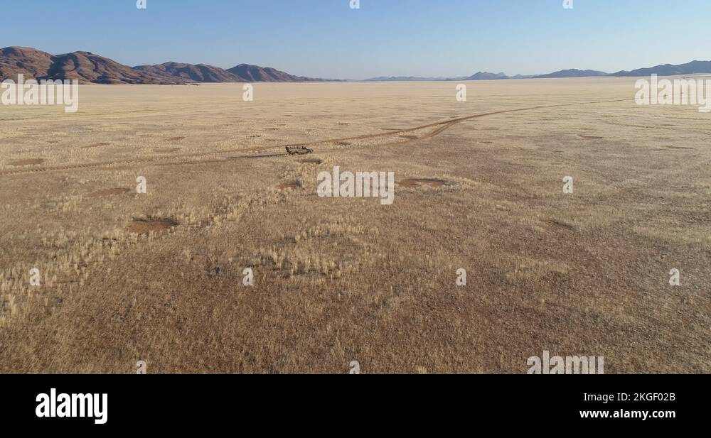 4K high tilt up aerial view of a 4x4 safari vehicle driving on a sand ...