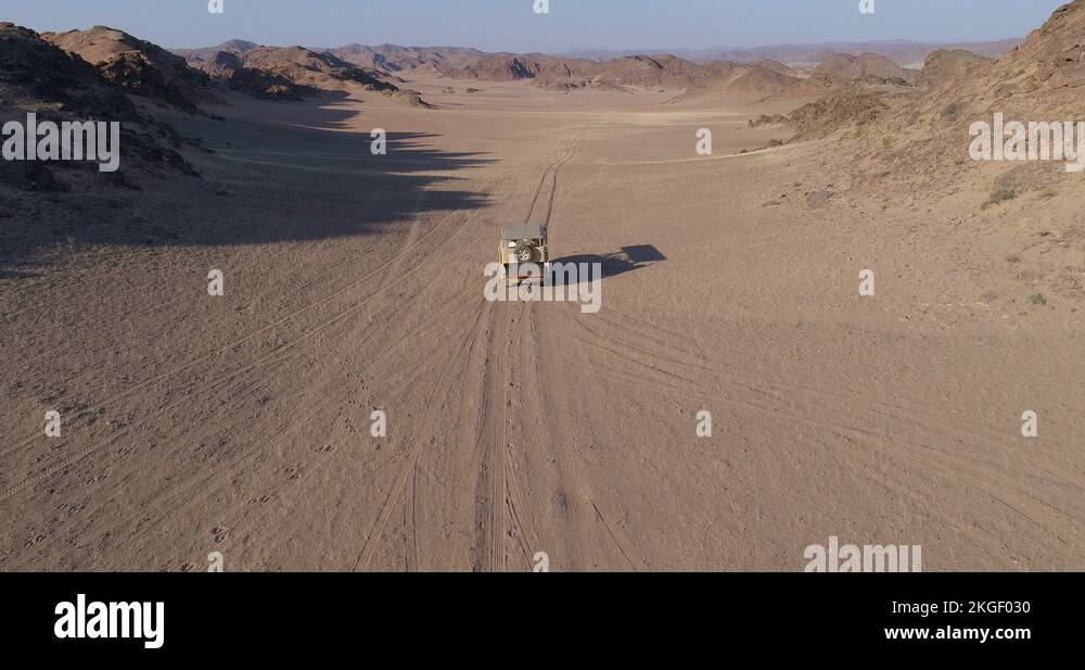 4K aerial rear view of a 4x4 safari vehicle driving in on a sand track ...