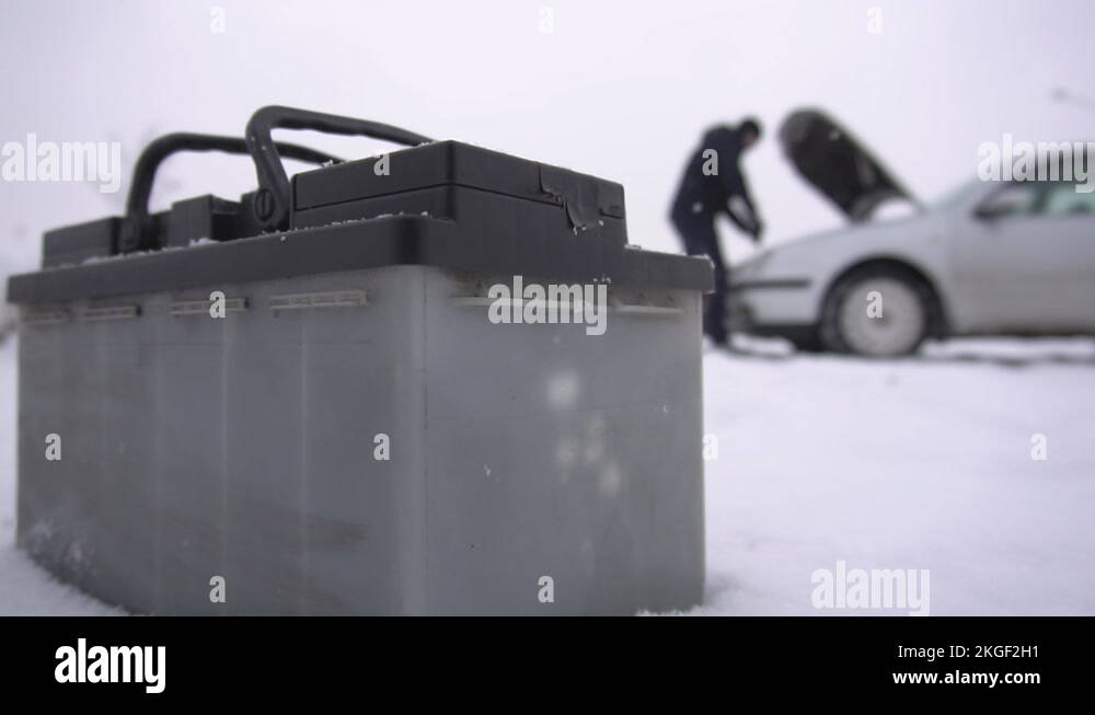 A man is repairing a car in the foreground is a battery, cold start ...