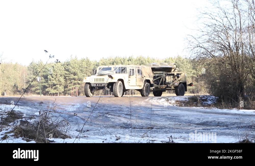 U.S. Army Humvee jeep towing trailer driving onto track covered in ice ...