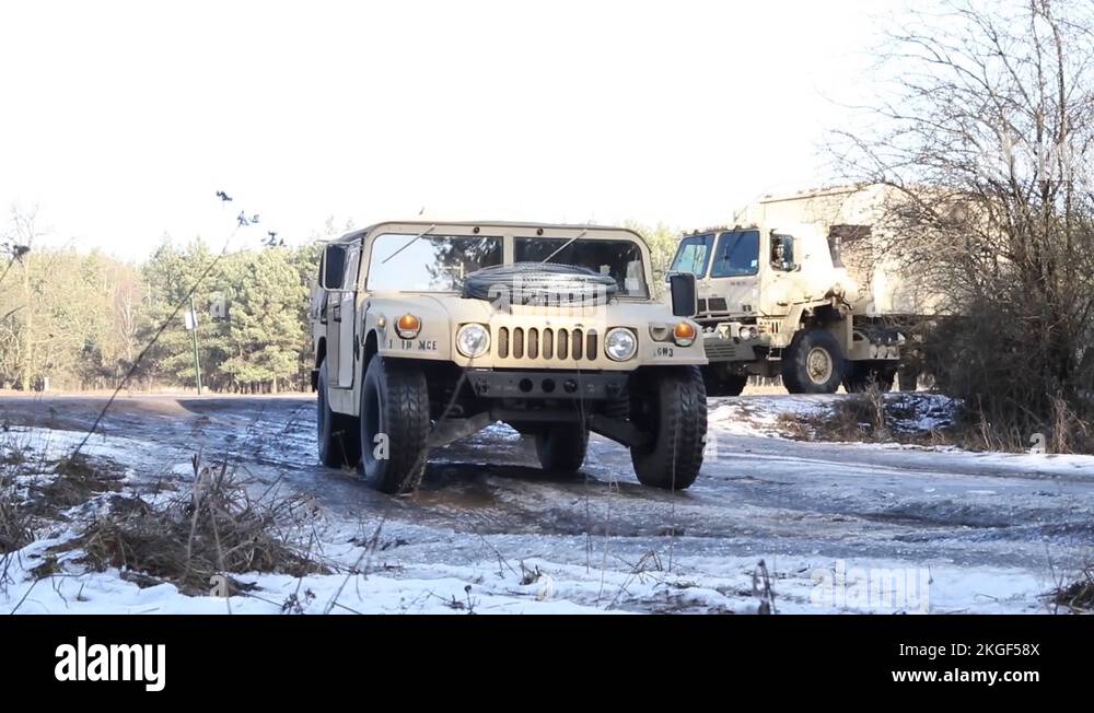 U.S. military vehicles driving in convoy onto track covered in ice and ...