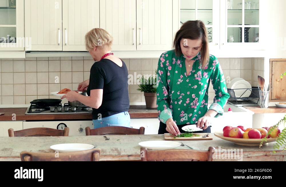 Mother and daughter talking during preparation dinner in the kitchen ...