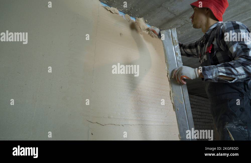 builder in work wear putting plaster on aerated concrete block wall ...