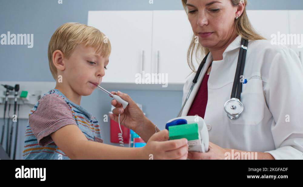 Pediatrician using a thermometer to check temperature of sick boy with ...