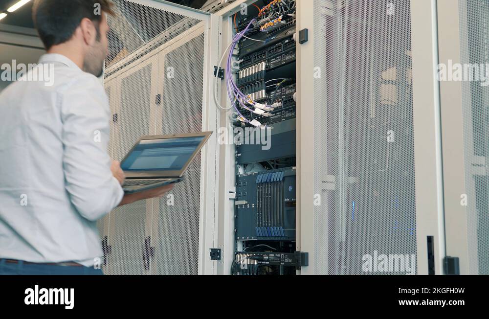 Man Working On Laptop In Server Room Checking Rack Server Cabinet And ...