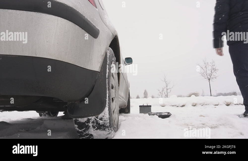 A man installs a car battery in a car, cold winter start of a diesel ...