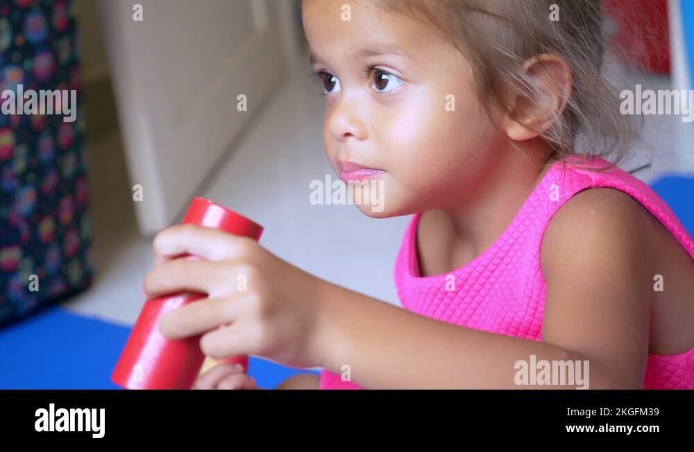 Little Asian cute girl playing cubes, sitting on a color floor. The ...
