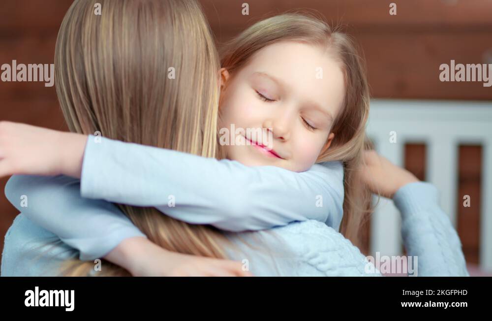 Close-up face of little baby girl gives big hug to her mother and ...