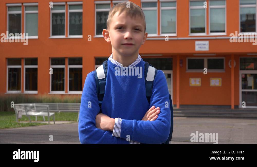 A young boy shakes his head at the camera with his arms folded across ...