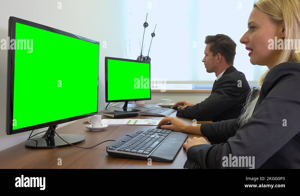Two office workers, man and woman, work on computers with green screens and talk Stock Video ...