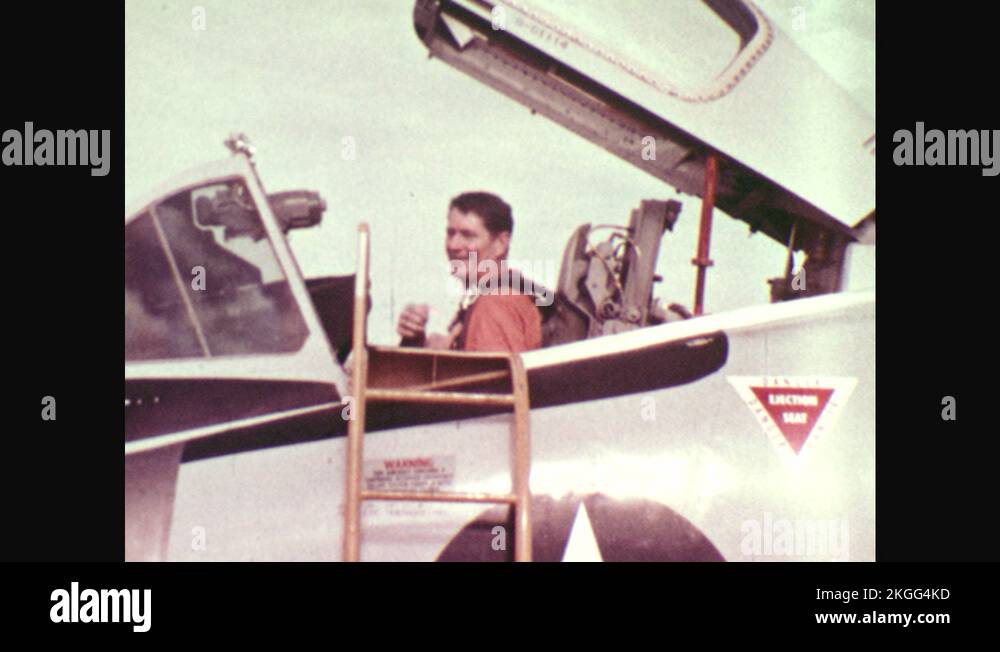 1970s: Pilot in cockpit of fighter jet, unstraps himself. Pilot stands ...