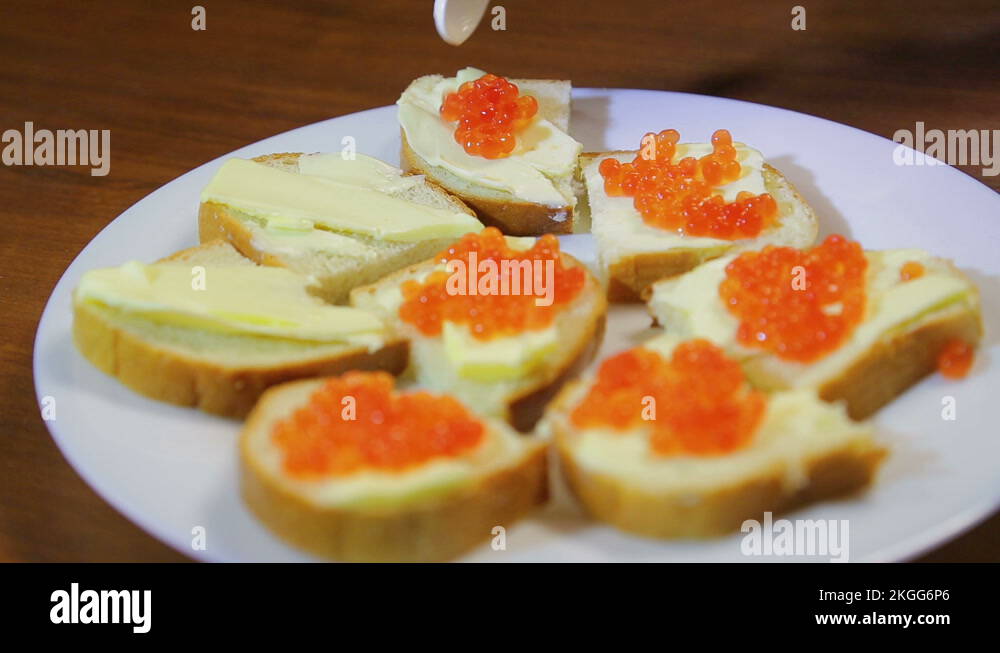 A woman smears red caviar with a spoon of canapes with butter Stock ...