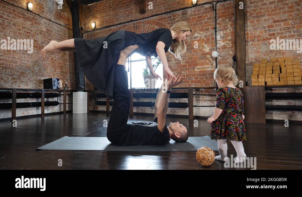 027 Acro yoga studio family father practice a pose with mother and baby ...