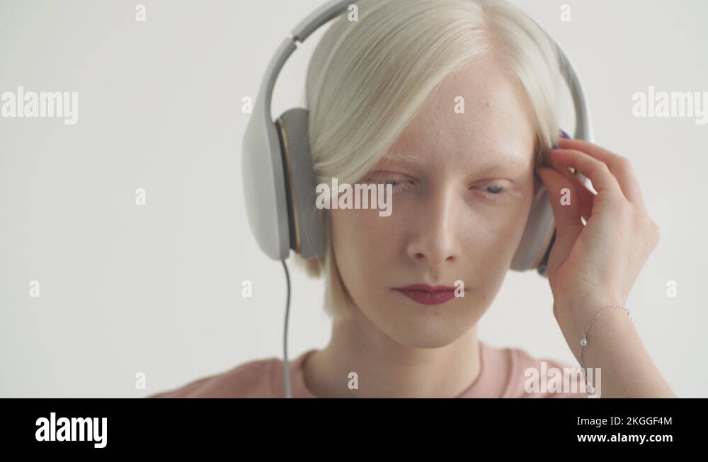 Young albino girl in the white earphones listening to music. Girl ...