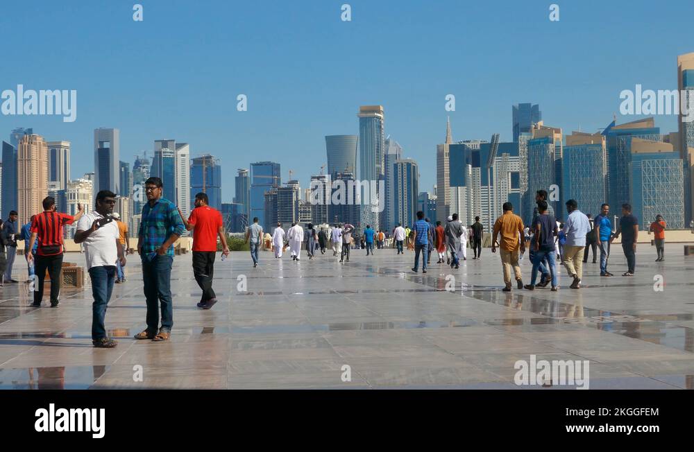 Crowd of People walking towards Doha downtown skyline and skyscrapers ...