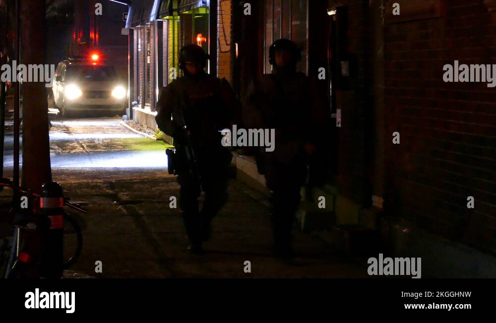Two cops with rifle walking by cameraman while going to hostage scene ...
