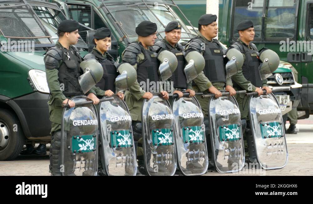 Row of 6 riot officers standing guard with shields placed on the ground ...