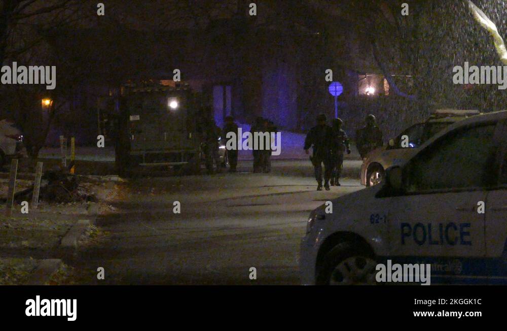 Numerous tactical police officers walking around crime scene at night ...