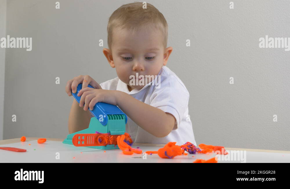 A 2-year-old preschool kid playing with modeling clay (compound). Early ...