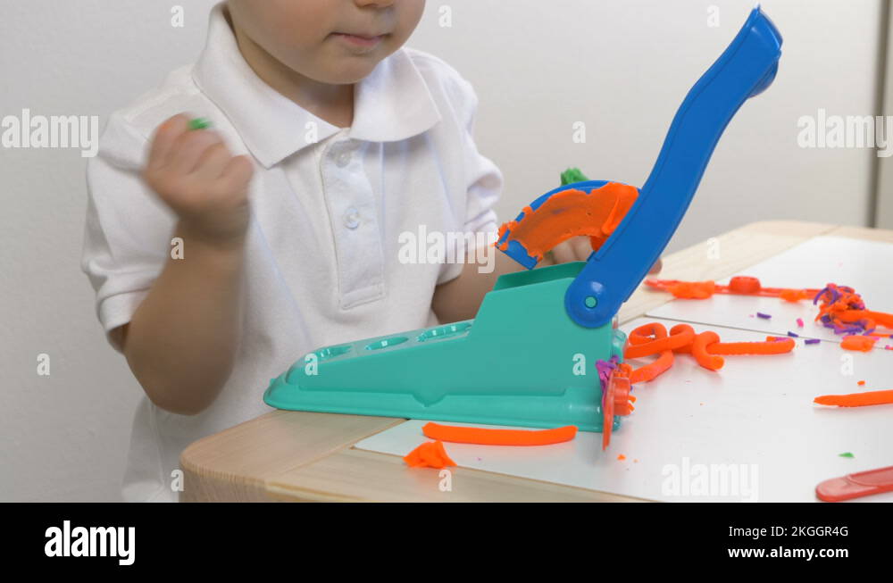 A 2-year-old preschool kid playing with modeling clay (compound). Early ...