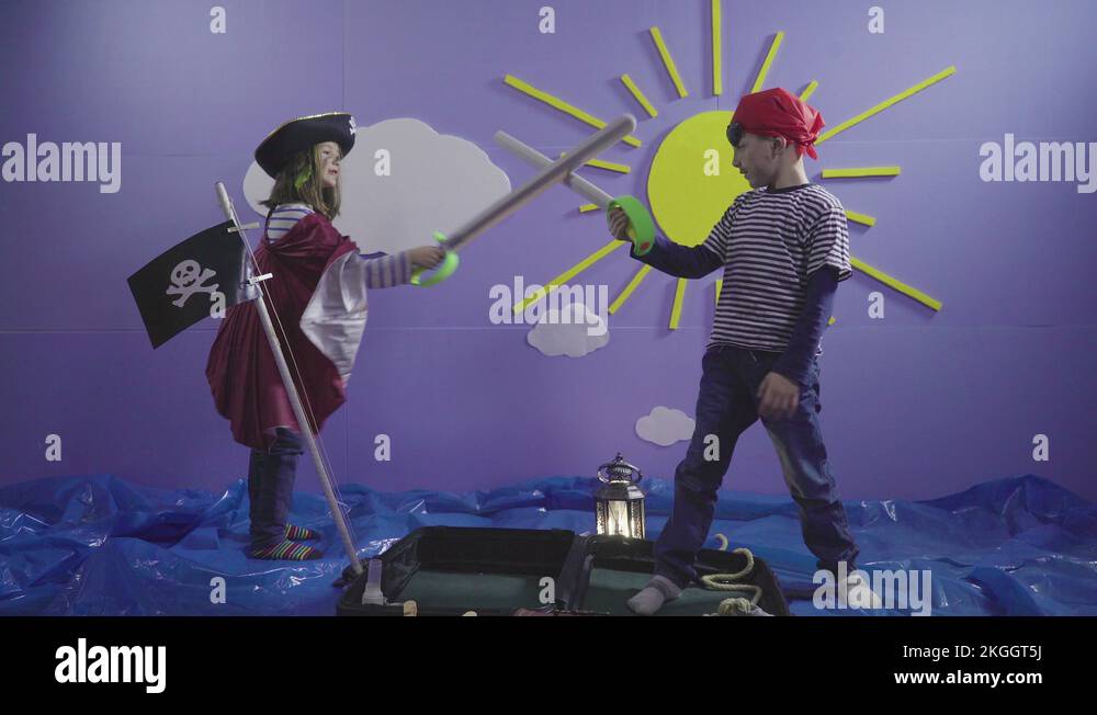 Little boy and girl pirates playing game and fencing with swords on sea ...