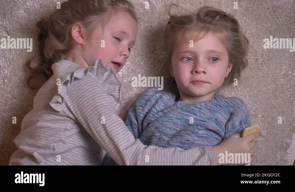 Top shot portrait of two small funny girls hugging and kissing joyfully ...