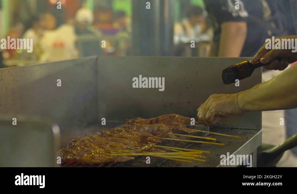 Asian man making chicken wings on a griddle at a night market in Kuala ...