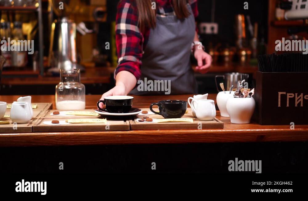 Concentrated female barista busy working at bar counter in coffee shop ...