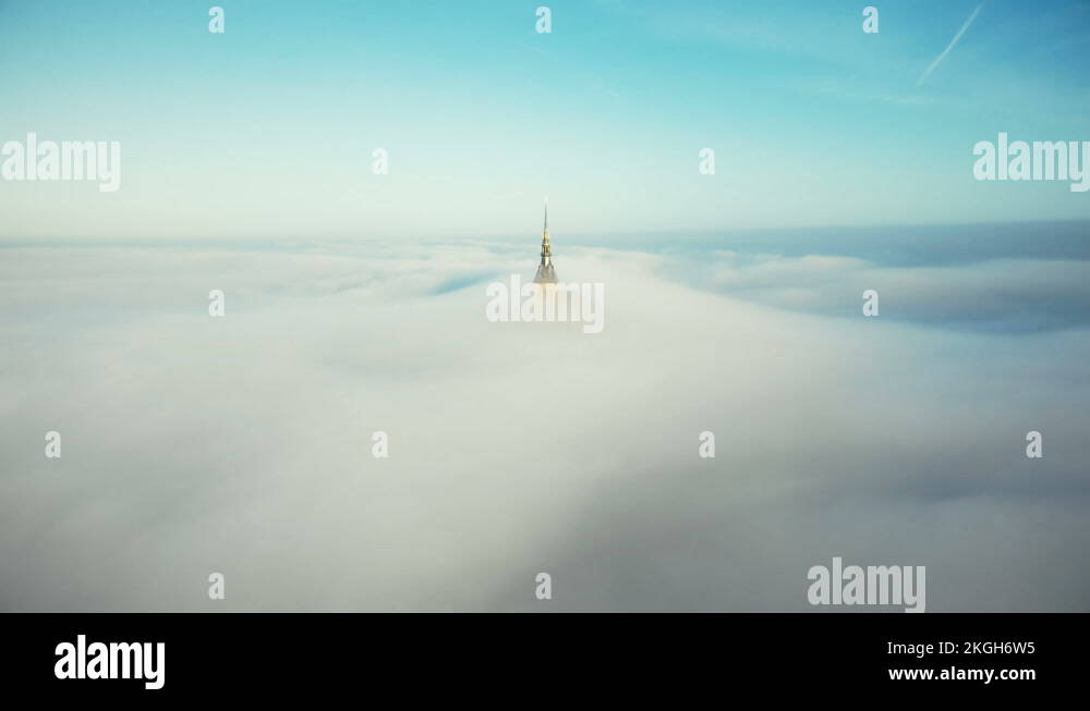 Drone rising above Mont Saint Michel castle spire covered by ethereal ...