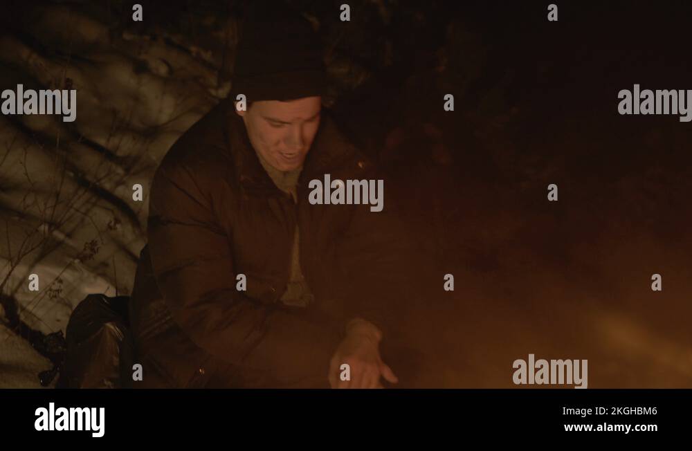 Homeless man gets and eats a roll with smile on face at campfire in ...