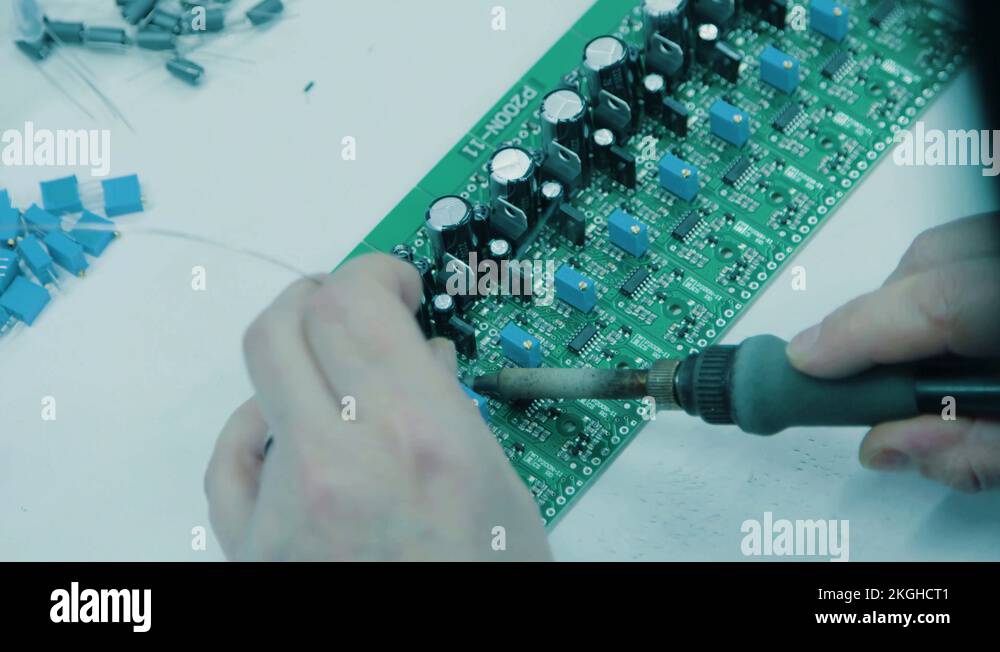 Industrial setup. Factory worker soldering components on a printed ...
