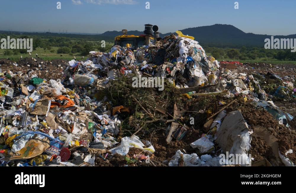 4K close-up view of a bulldozer churning over tons of garbage on ...