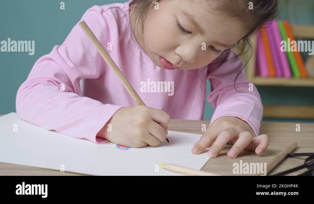 Happy child little asian girl writing in a book in class room at home ...