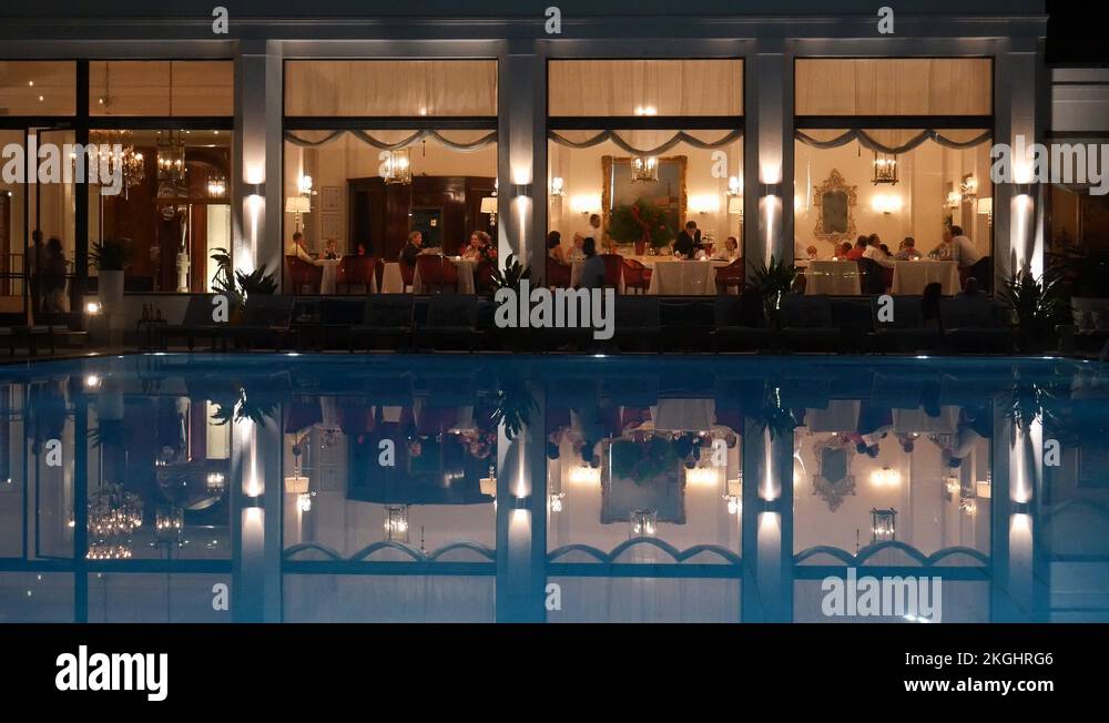Busy poolside restaurant reflected on swimming pool at the luxurious ...